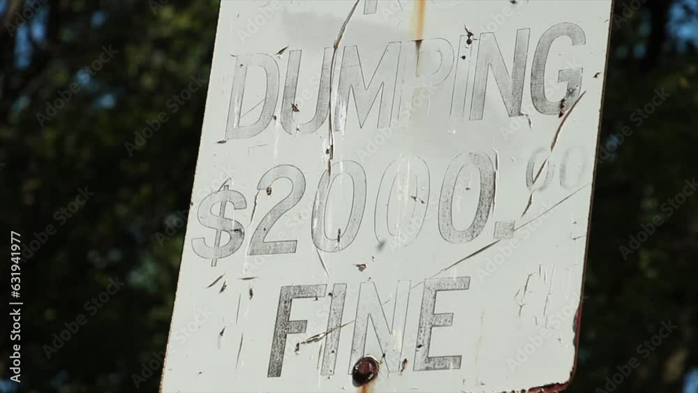 old worn and faded dumping $2000 fine sign with light black writing on ...