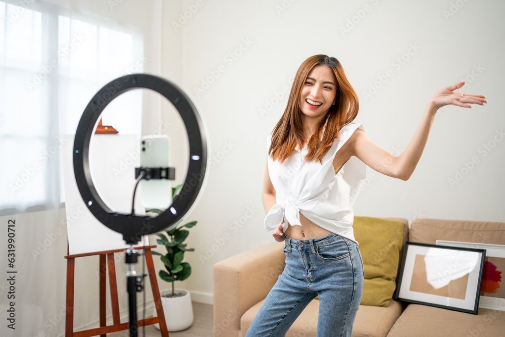 Young trendy influencer asian woman dancing on mobile phone at home in ...