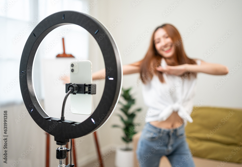 Young trendy influencer asian woman dancing on mobile phone at home in ...
