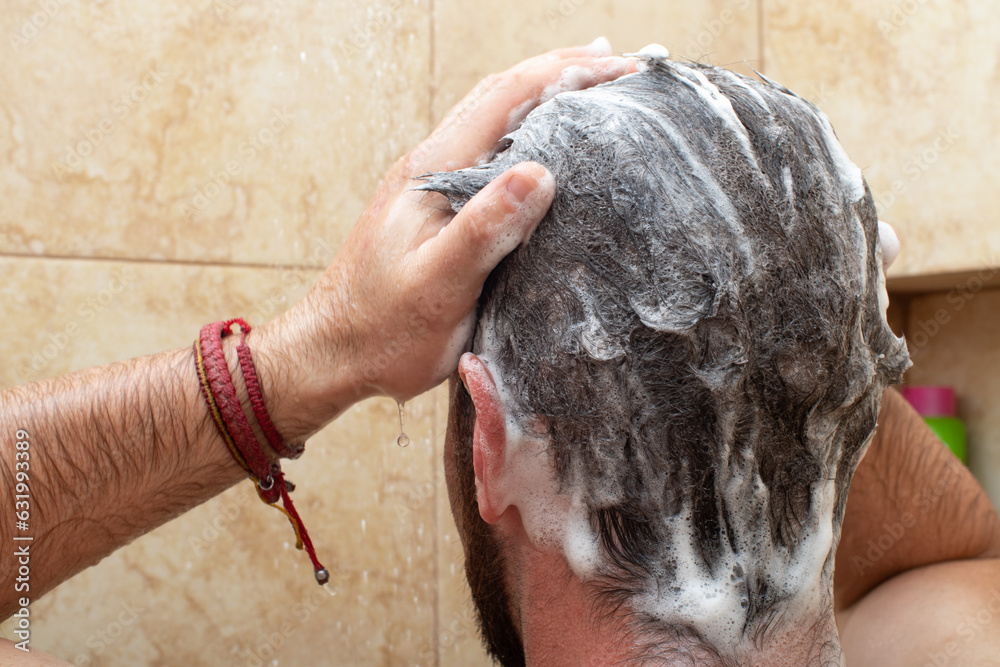 young man washing head hair with shampoo in the shower, male personal ...