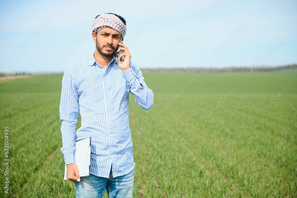Portrait of happy young Indian man farmer standing in agriculture land ...