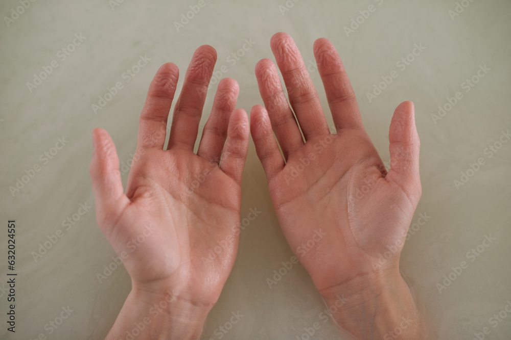 Wrinkly human hands lying open on water surface in bathtub, directly ...