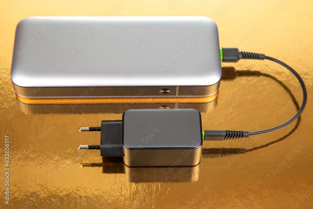 Power bank and charging plug with cable on a golden background ...