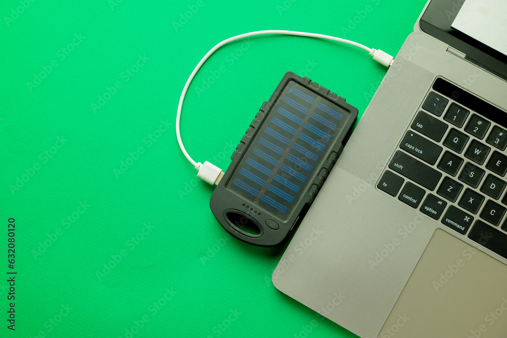 A modern laptop is being charged from a solar-powered charging station ...