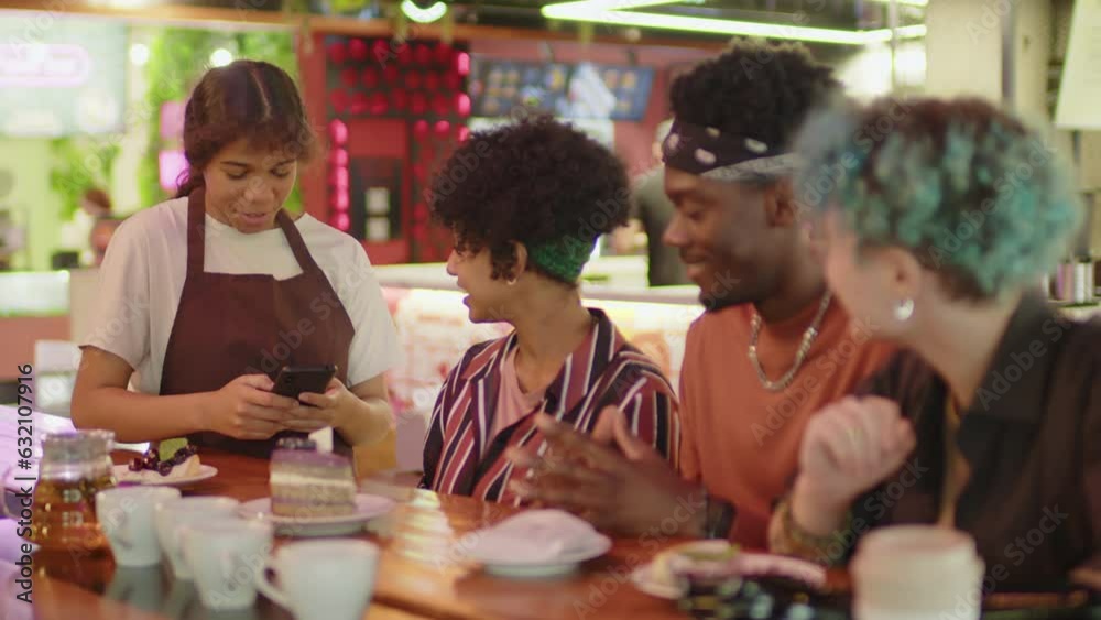 Young African American waitress in apron using smartphone while taking ...