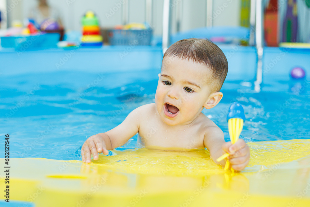 Little cheerful 2-year-old boy is learning to swim in the pool ...