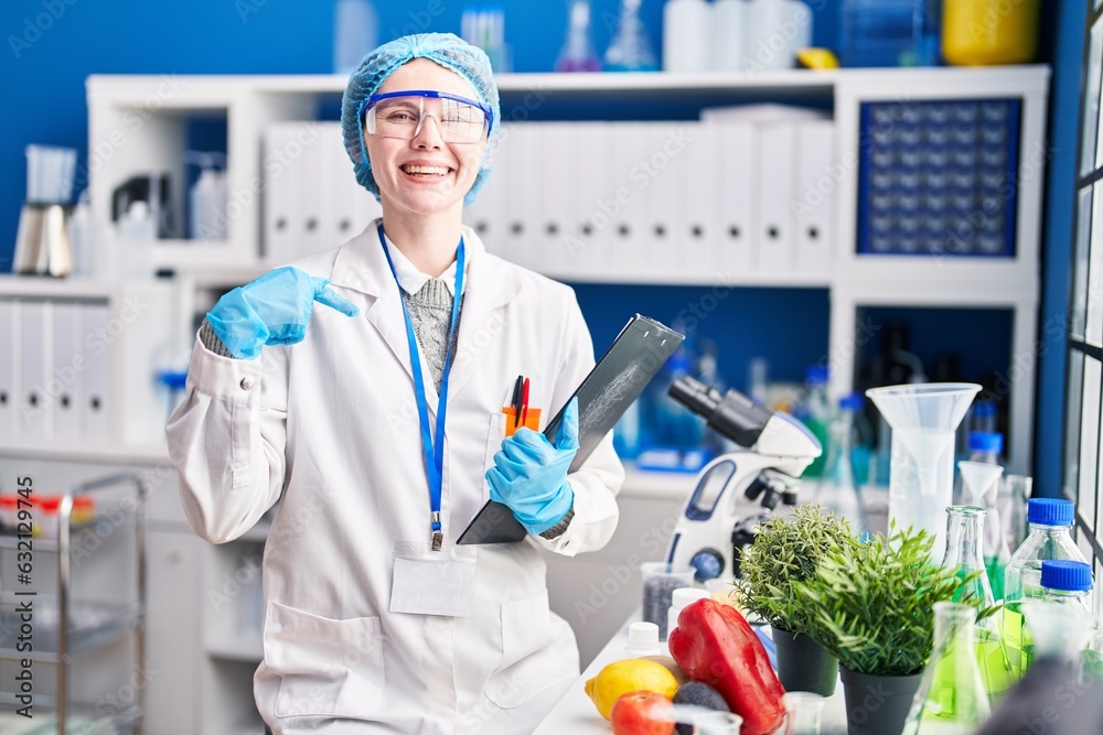 Beautiful woman working at scientist laboratory with food pointing ...