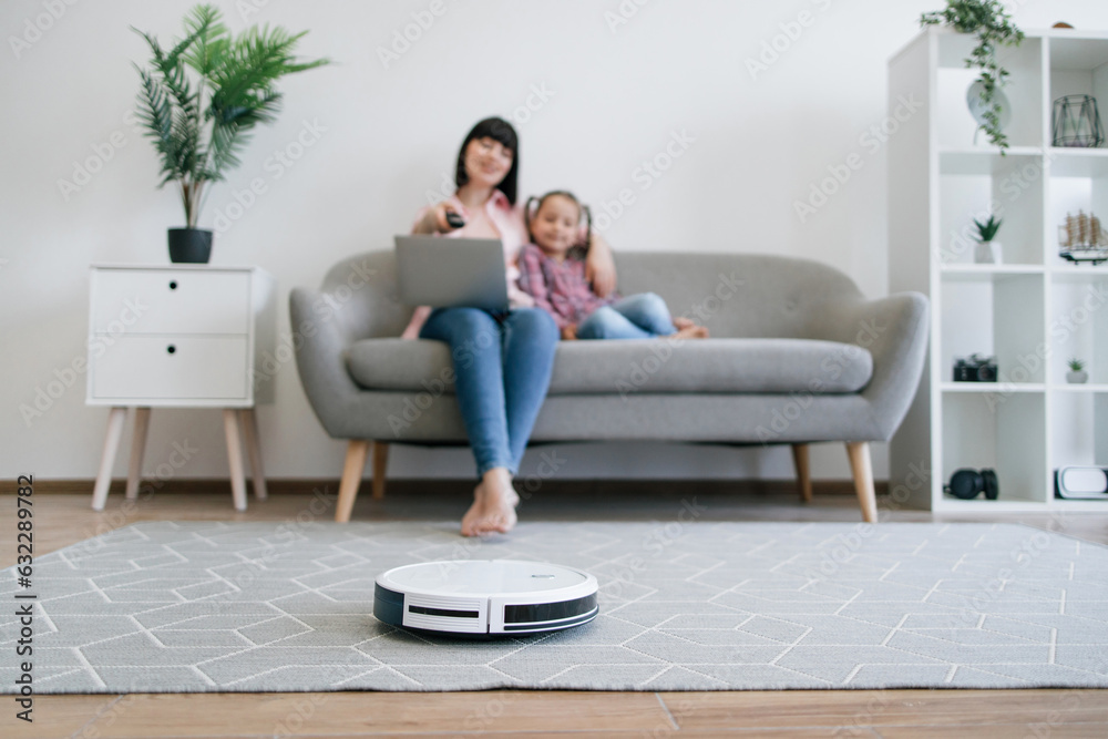 Focus on automatic cleaning robot controlled remotely by brunette woman ...