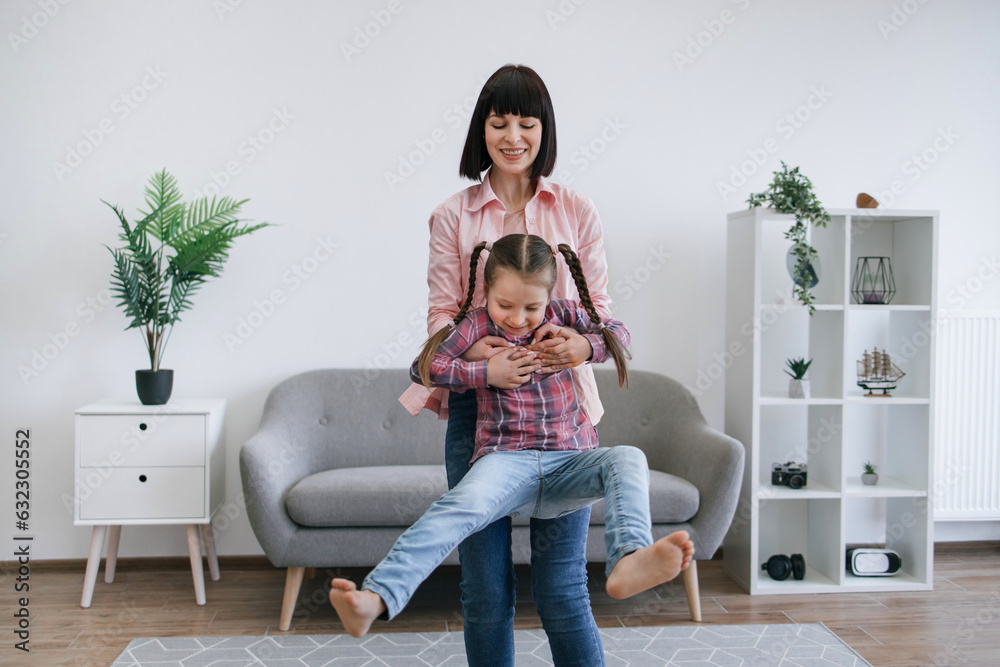 Strong sporty mom twirling preteen child around with hands under ...