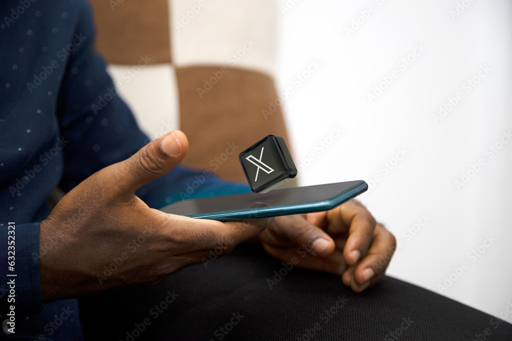 Black Hand holding mobile phone with X logo hovering on screen in ...