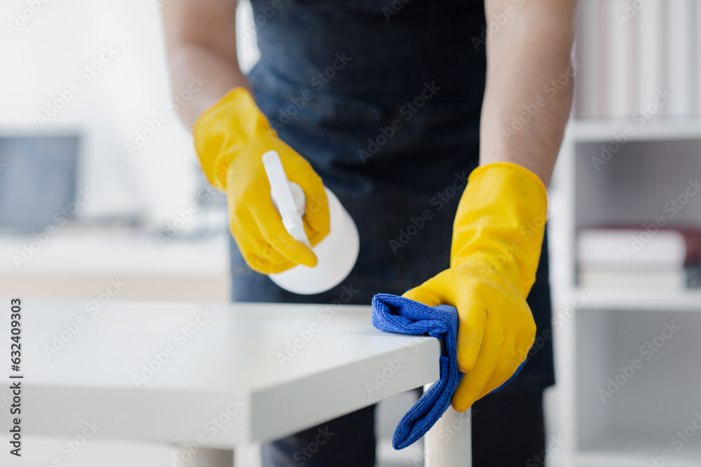 Person cleaning the room, cleaning staff is using cloth and spraying ...