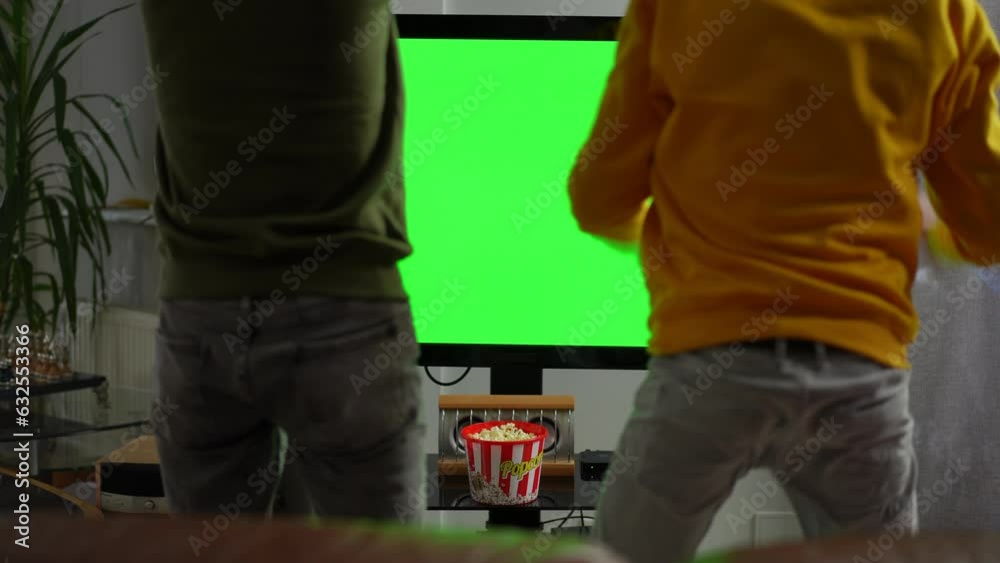Shooting over shoulder of two young men watching green screen plasma ...