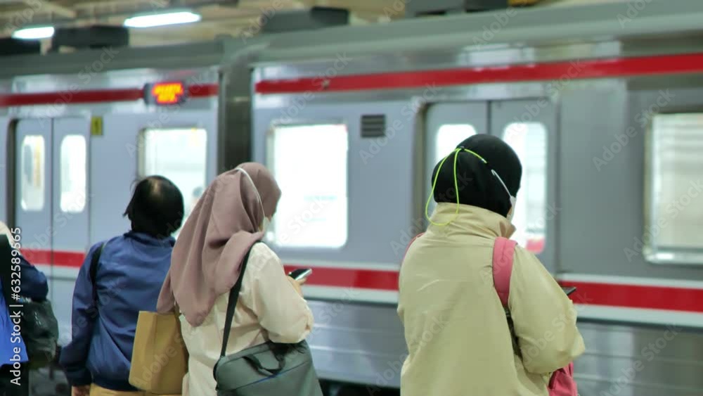 Female passengers waiting for an incoming commuter train at station in ...