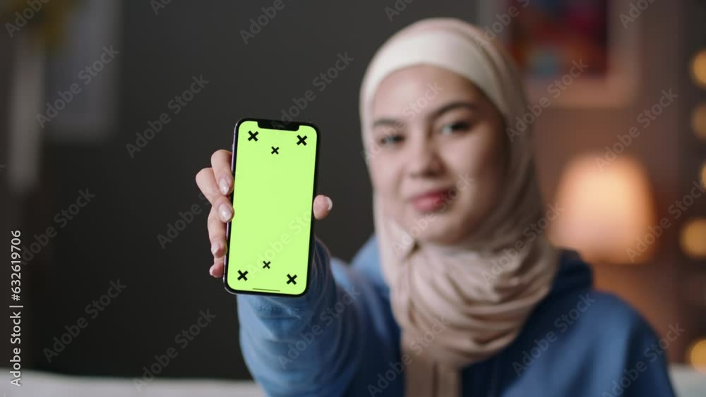 Smiling covered Muslim woman in hijab showing smartphone screen with ...