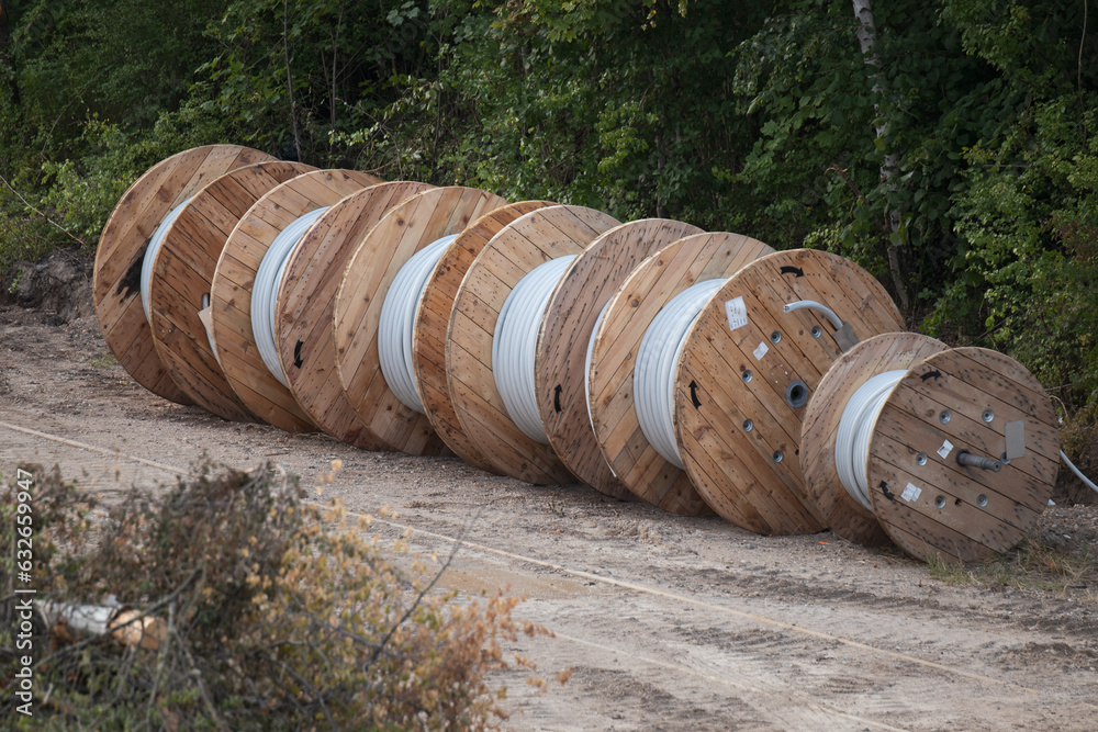 Huge wheel of coiled up electrical fiber cables on forest contruction ...
