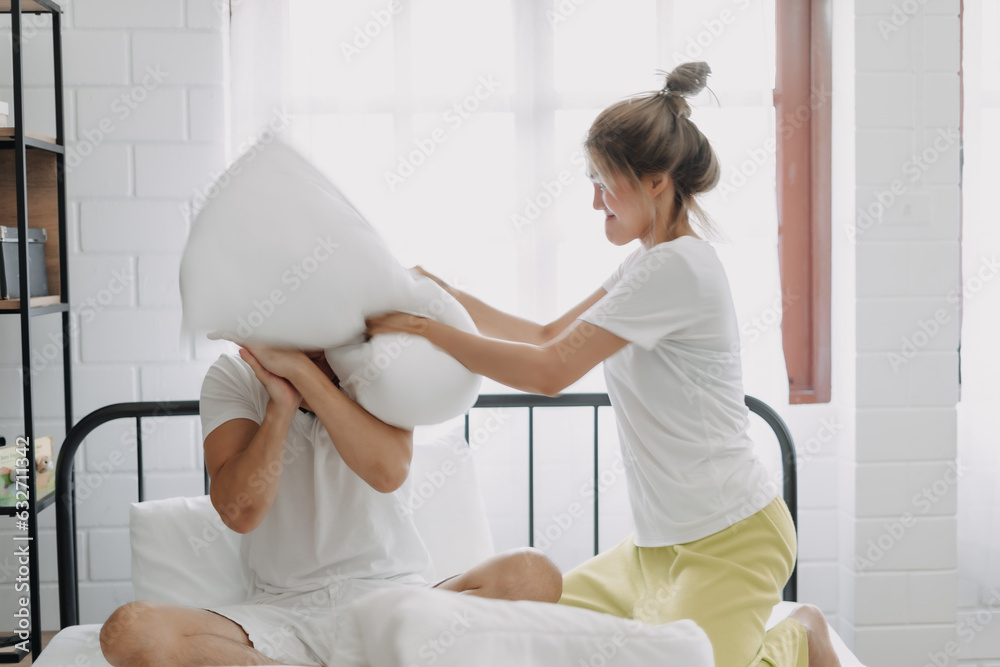 Funny asian couple angry wife hit husband with pillow in white bedroom. foto de Stock | Adobe Stock