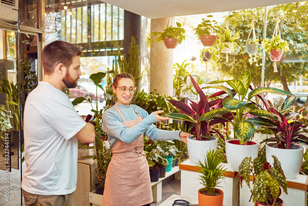 beautiful caucasian female employee owner helping or showing plants to ...
