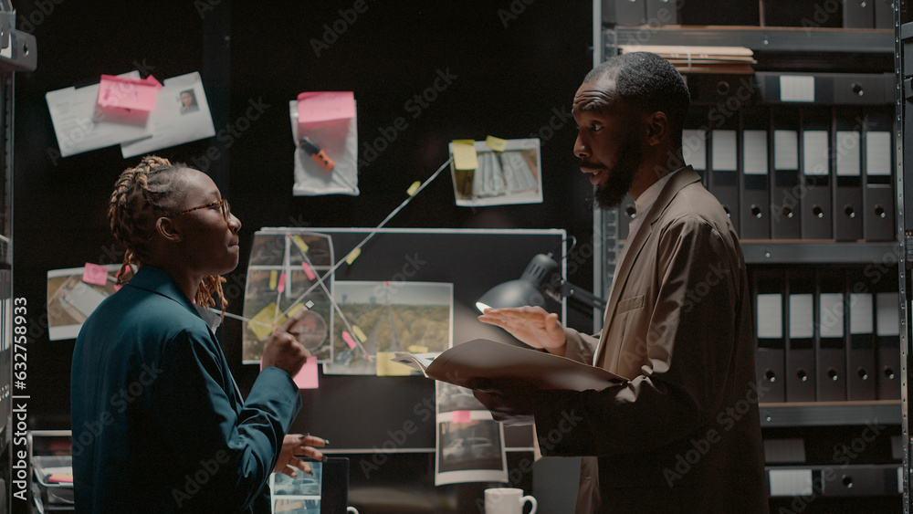Detectives colleagues examining criminal files in office, looking at ...