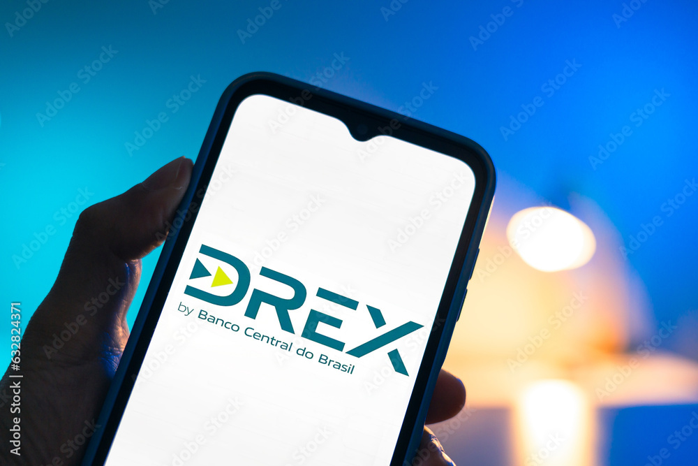 Hand holding a smartphone displaying the DREX logo, which is the name ...