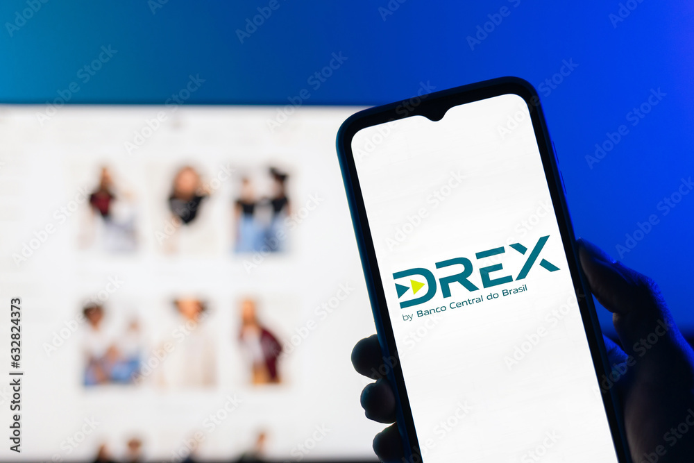 Hand holding a smartphone displaying the DREX logo, with a blurred ...