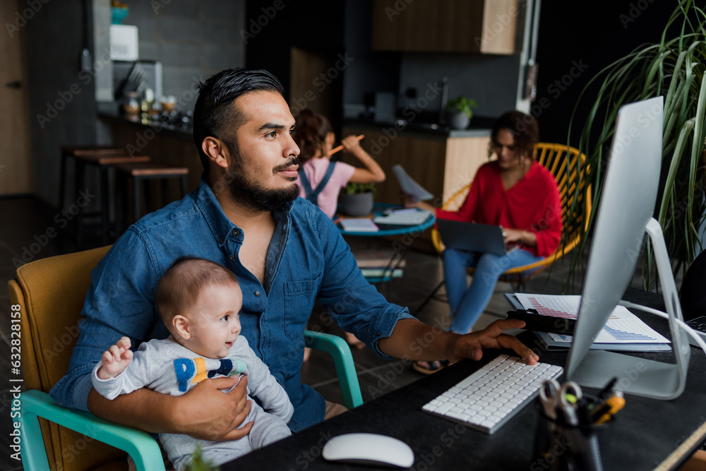 latin father using computer to work from home while he take care of his ...