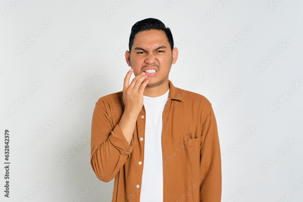 Dental problems. Unhappy young Asian man in casual shirt suffering from ...