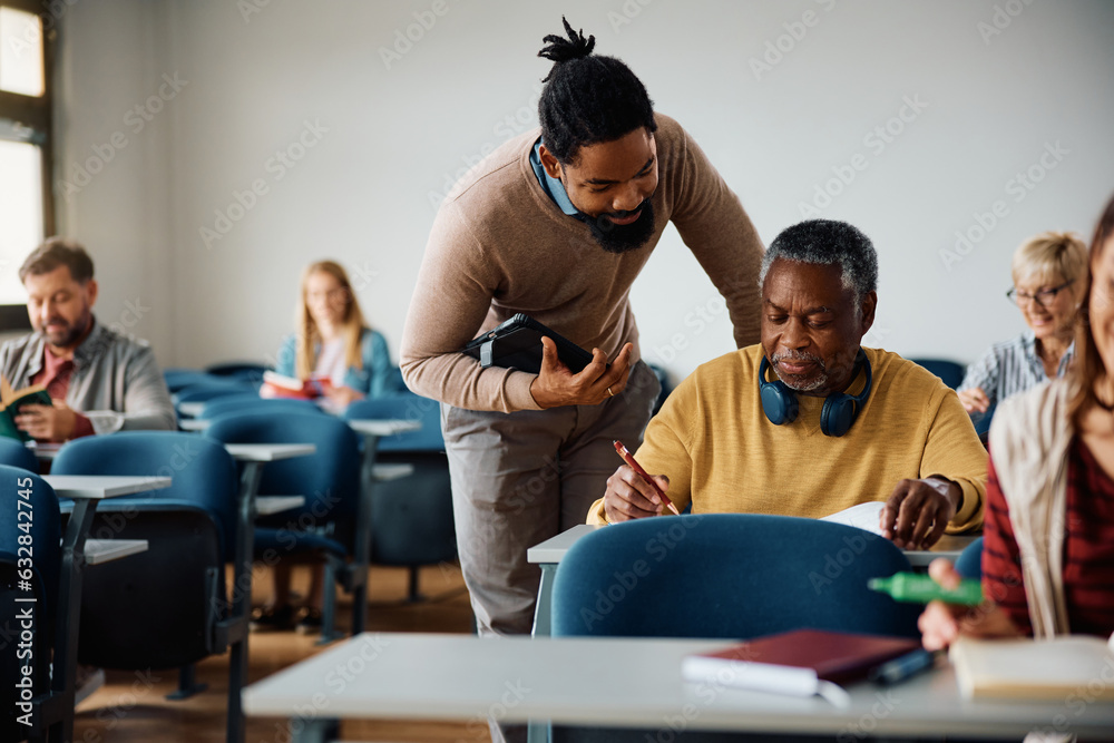 Black senior man learns with help of teacher while attending adult education course. Stock Photo ...