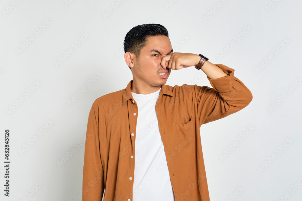 Young Asian man in casual shirt holding breath with finger on nose ...