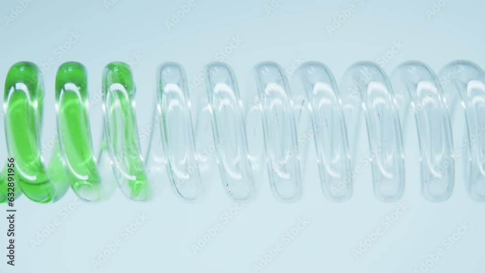 Green liquid flows down a glass spiral pipe. Test tube with spiral pipe ...