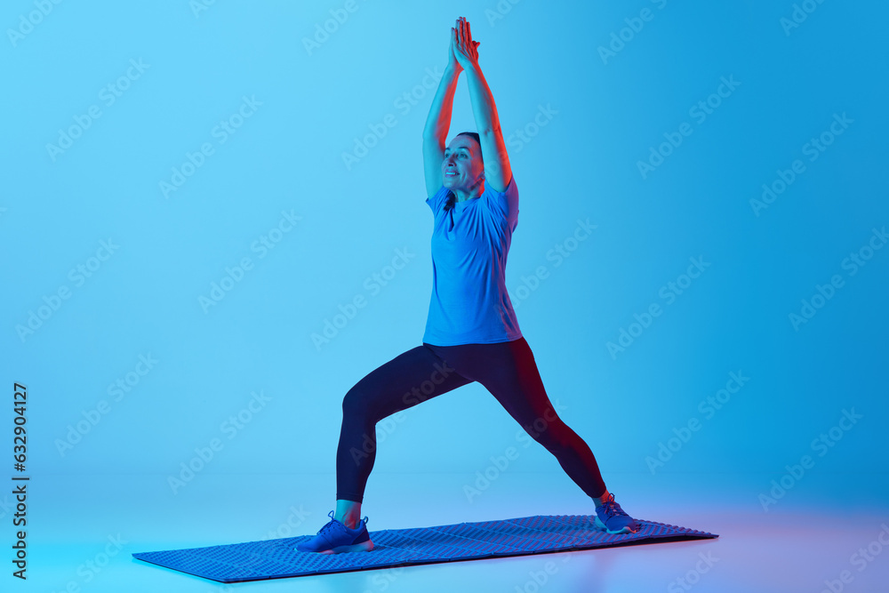 Keeping body toned. Woman training on fitness matt, stretching against ...