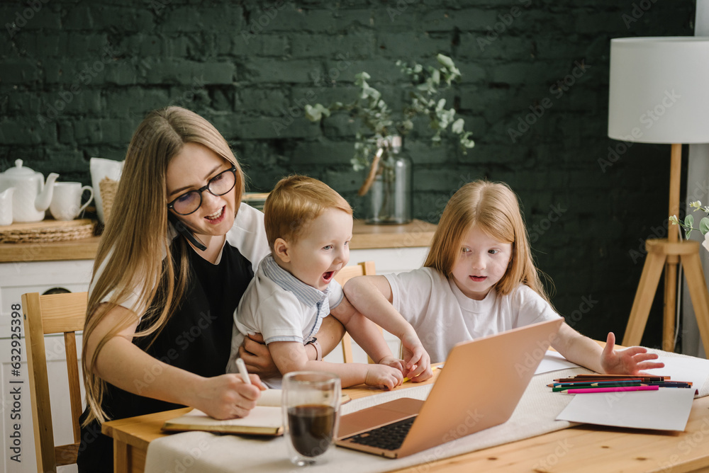 Woman working, learns on laptop computer. Mother working with kids at ...
