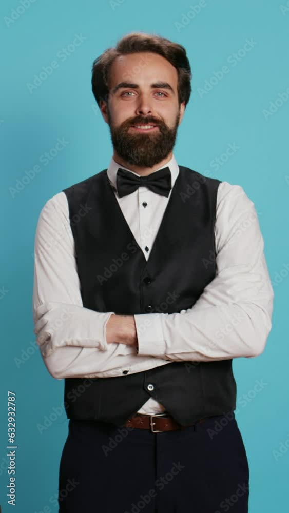 Vertical video Skilled bellhop wearing white gloves and posing against ...