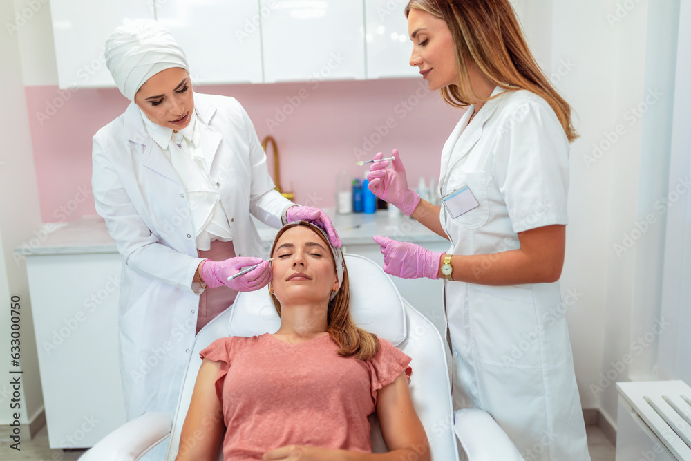 Cosmetologist drawing contour lines on the female's face before brow ...