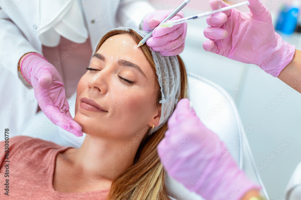 Cosmetologist drawing contour lines on the female's face before brow ...