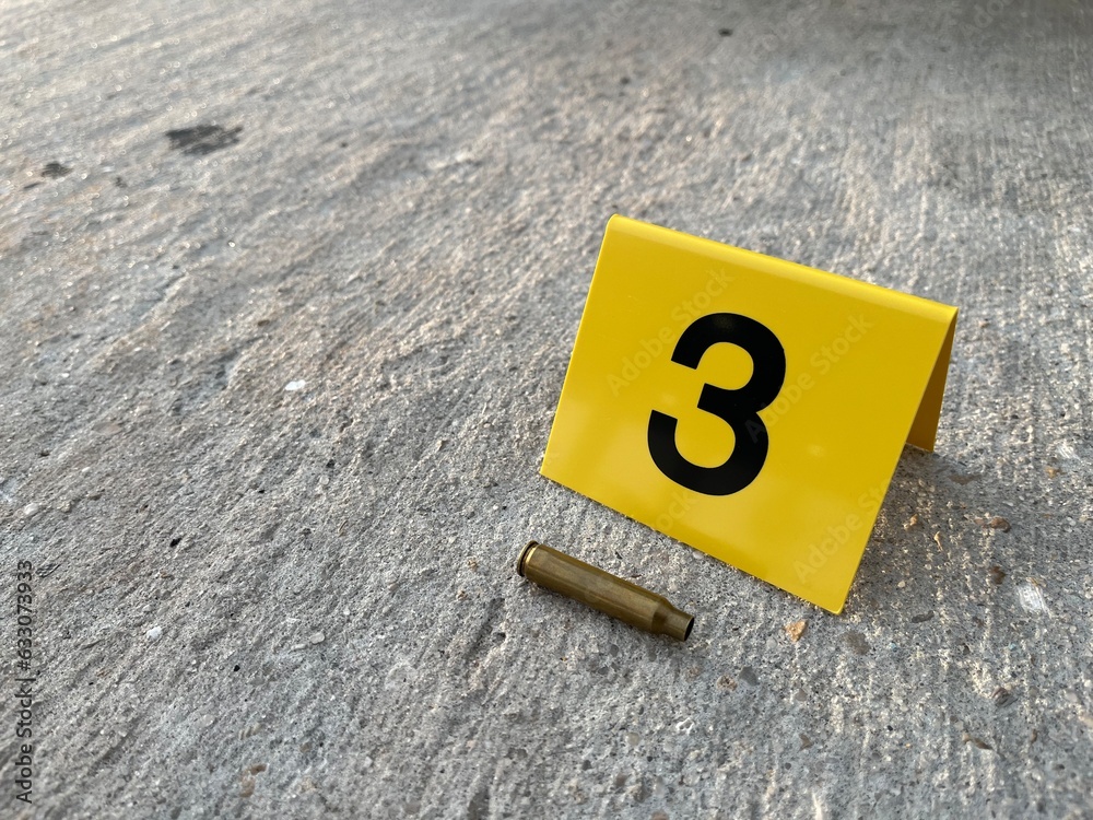 One yellow crime scene evidence marker on the street after a gun ...