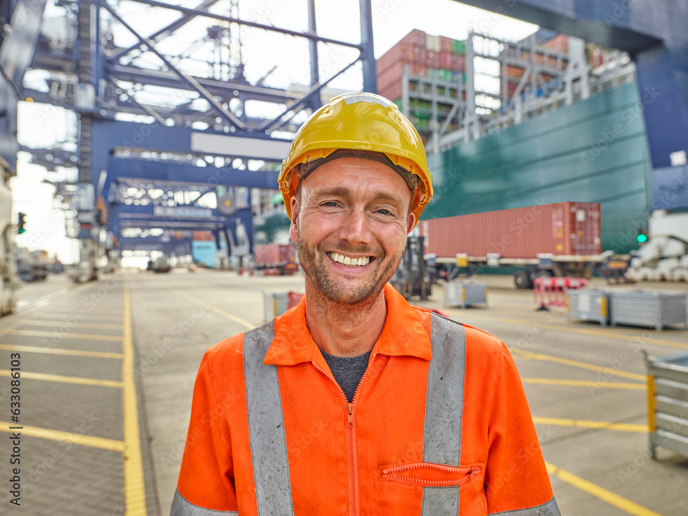 Smiling dock worker in reflective clothing and hard hat infront of ...