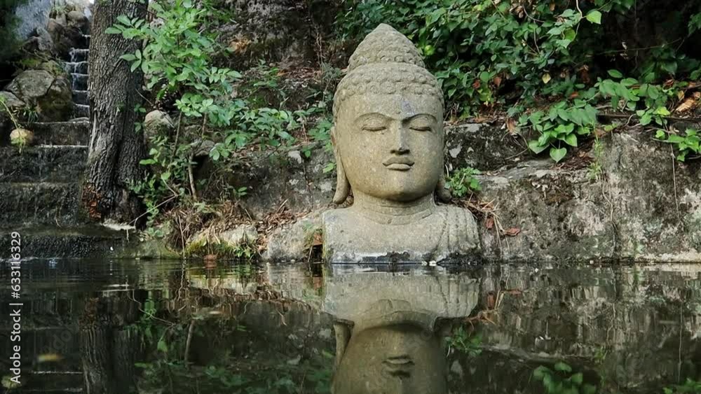 Stone antique statue of Buddha on a background of a waterfall stream in ...
