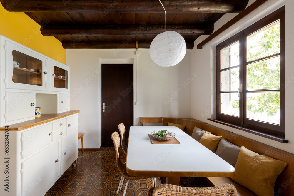 Empty dining room with only a table, chairs and a bench. On the left a ...