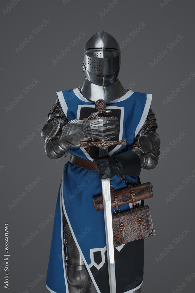 Medieval guard dressed in armor and blue surcoat holding a sword ...