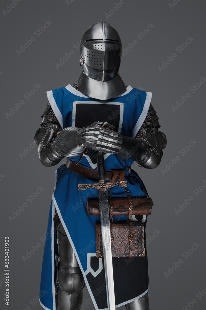 A medieval soldier garbed in blue surcoat and armor holding a sword ...