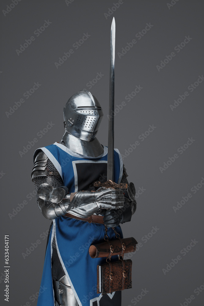Medieval guard dressed in armor and blue surcoat holding a sword ...