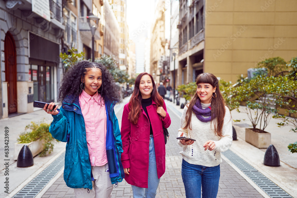 portrait multiracial group of three young women walking down the street ...