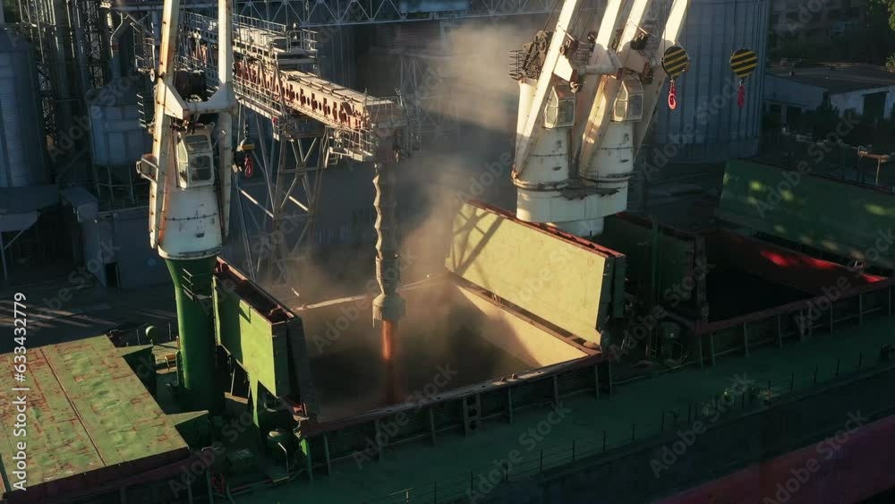 Aerial of wheat loading to bulker ship cargo hold at sea grain elevator ...