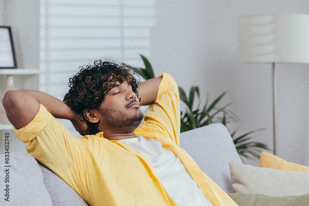 Young man relaxing alone at home on sofa, close-up Hispanic man with ...