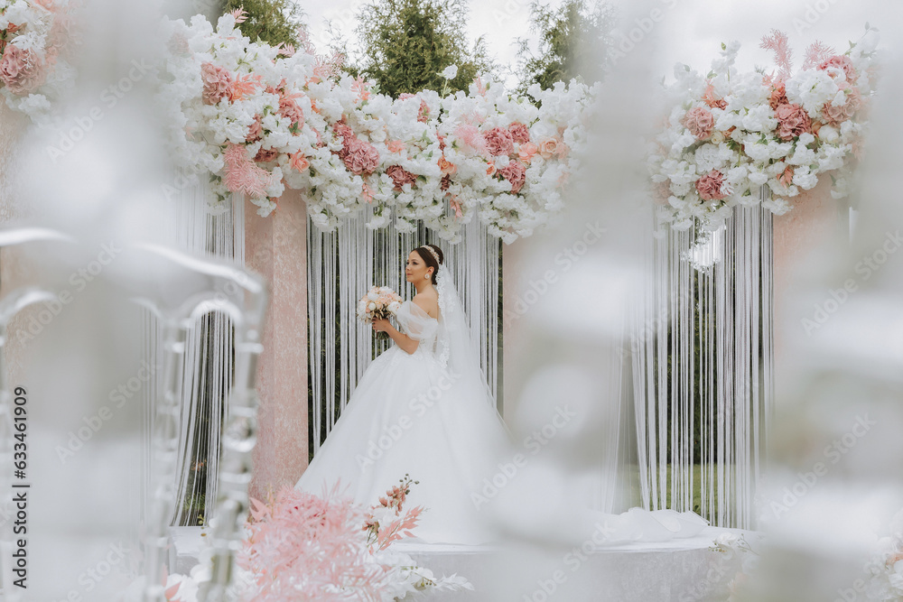 Attractive bride at the ceremony on her wedding day with an arch made ...