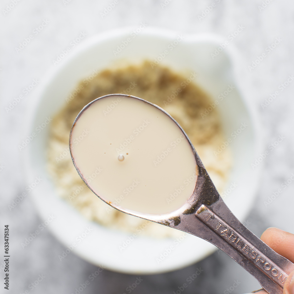 Top view of evaporated milk in a measuring spoon, vegan and alternative ...