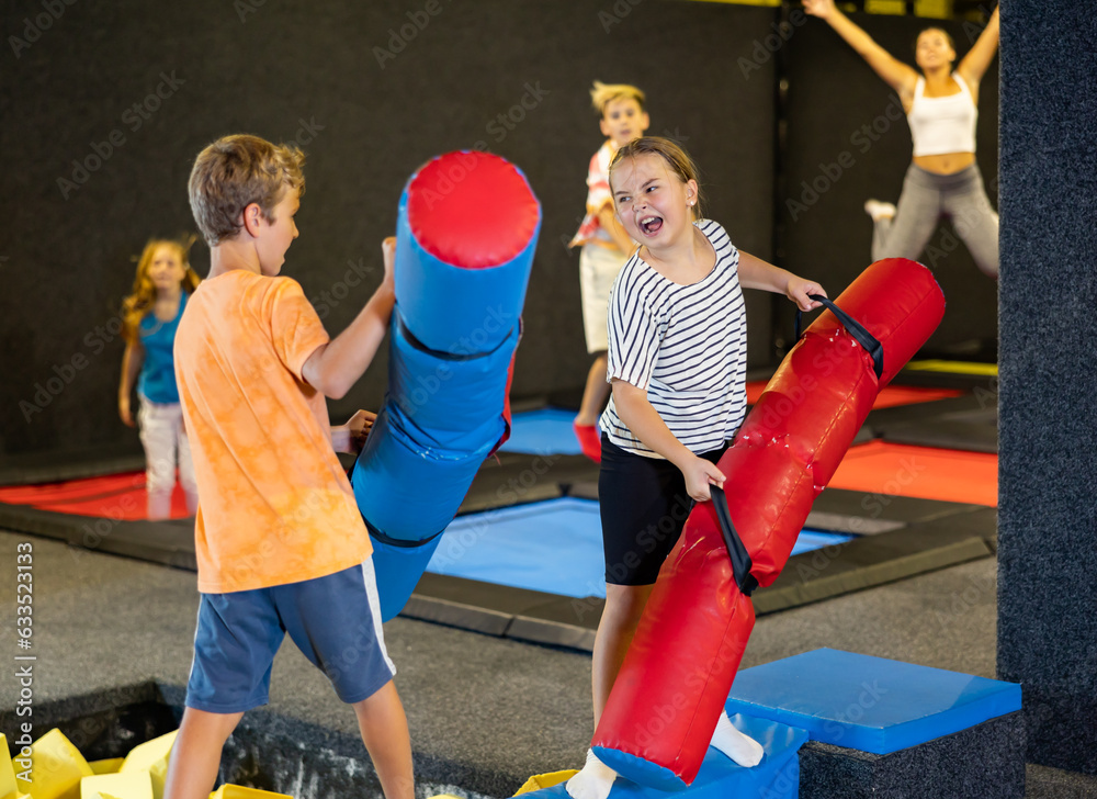 Excited children boy and girl having funny wrestling by inflatable logs ...