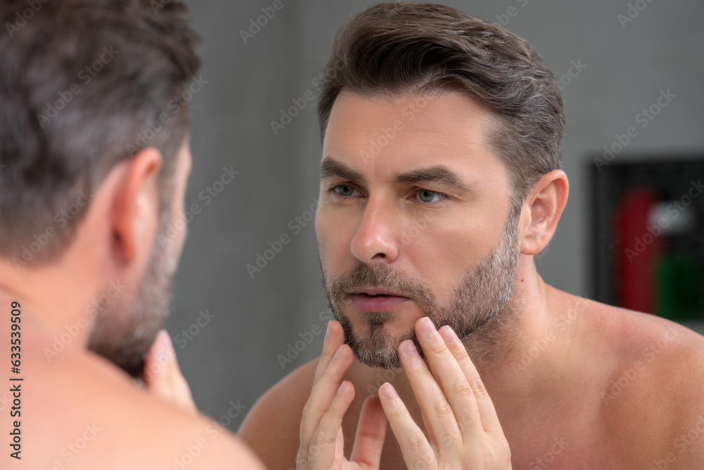 Foto de Close-up portrait of perfect brunet man touching chin and skin ...