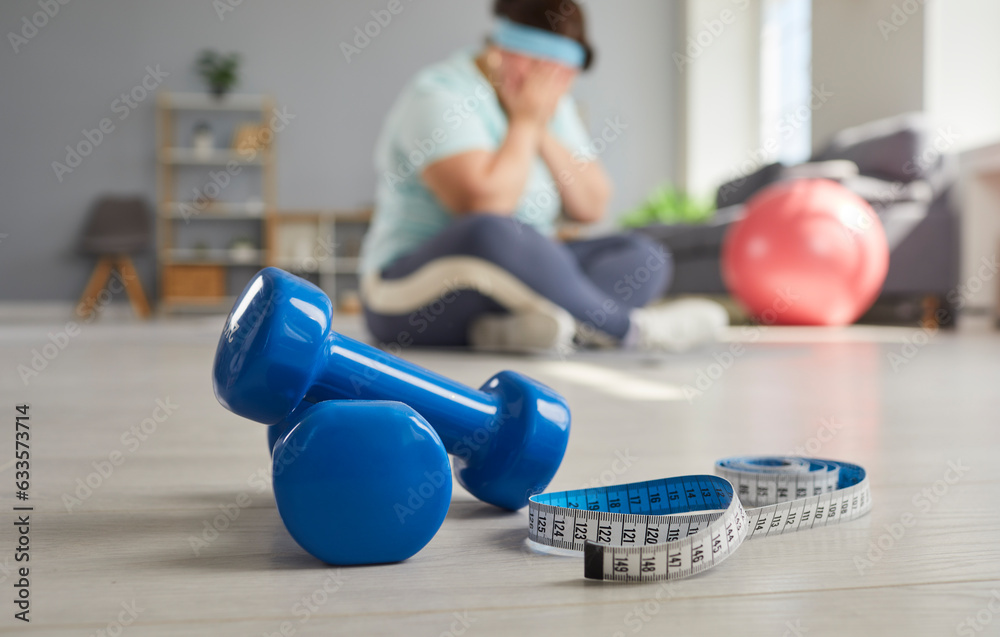 Overweight, obese upset woman sitting on floor with measuring tape ...