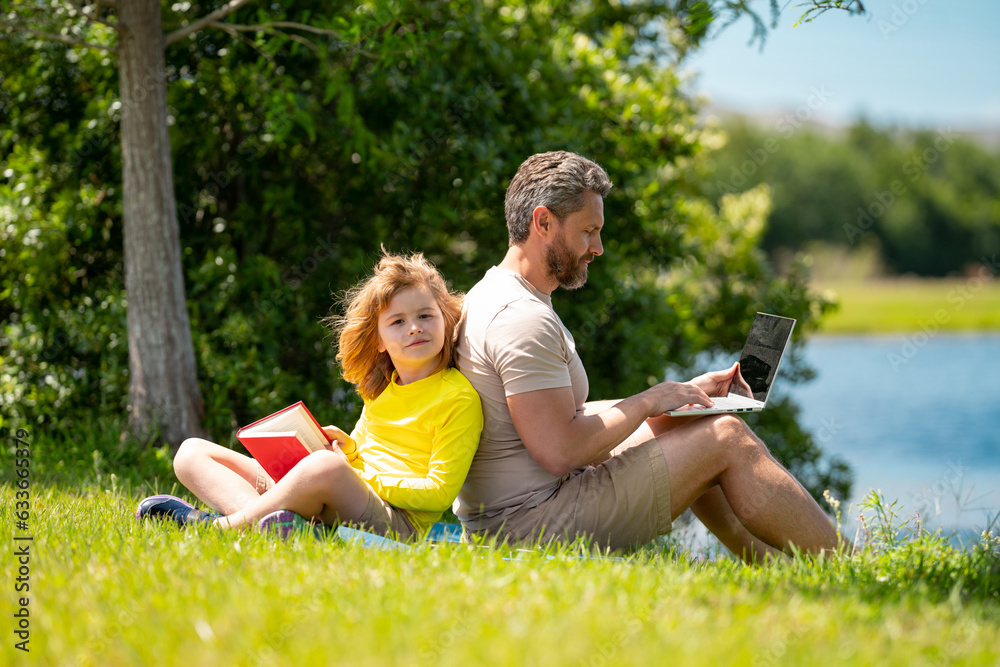 Father with his son reading book together in the summer park. Father ...